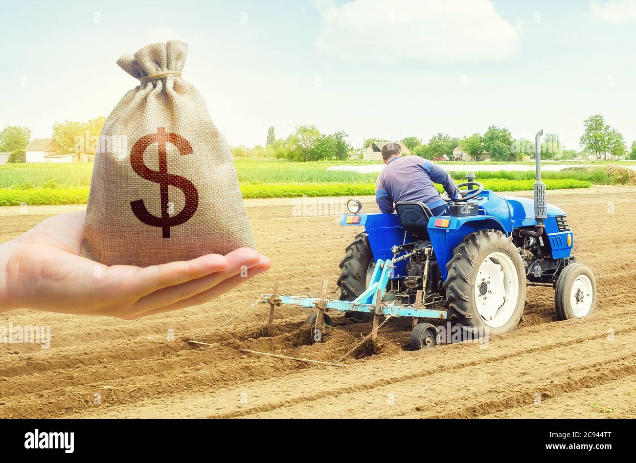A hand holds out a dollar money bag on a background of farmer on a ...