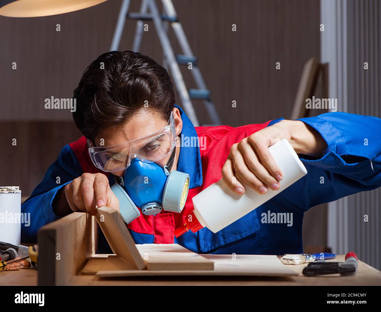 The young man gluing wood pieces together in diy concept Stock Photo ...