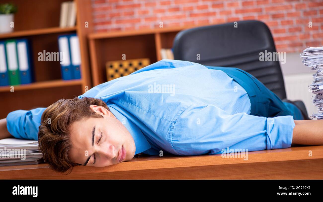 The young employee with excessive work sitting at the office Stock ...
