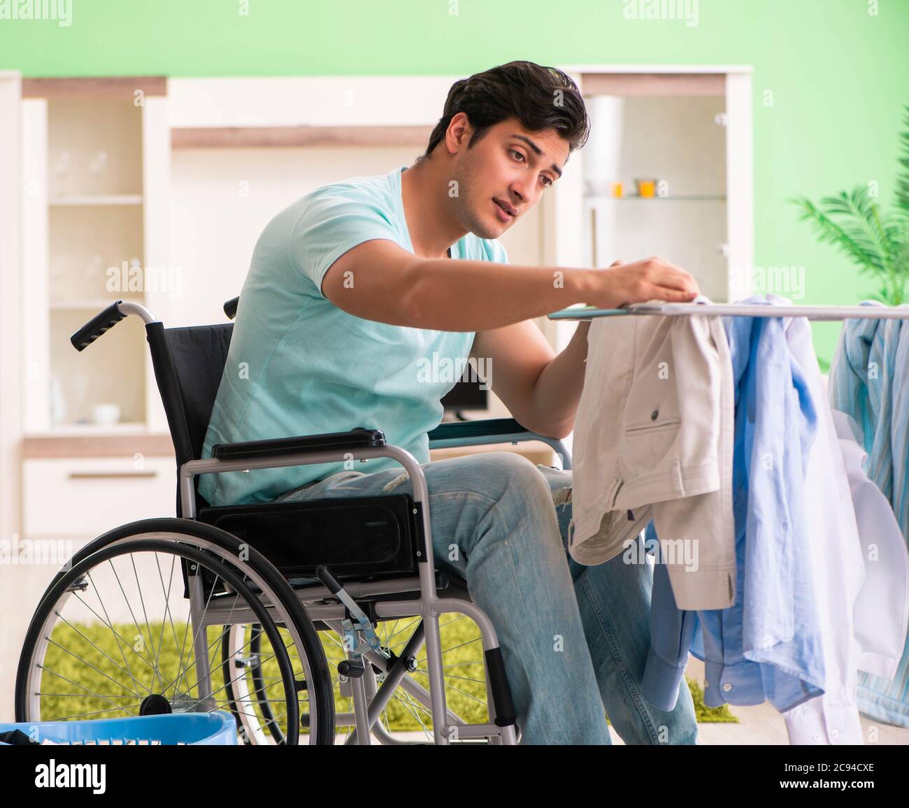The disabled man on wheelchair doing laundry Stock Photo - Alamy