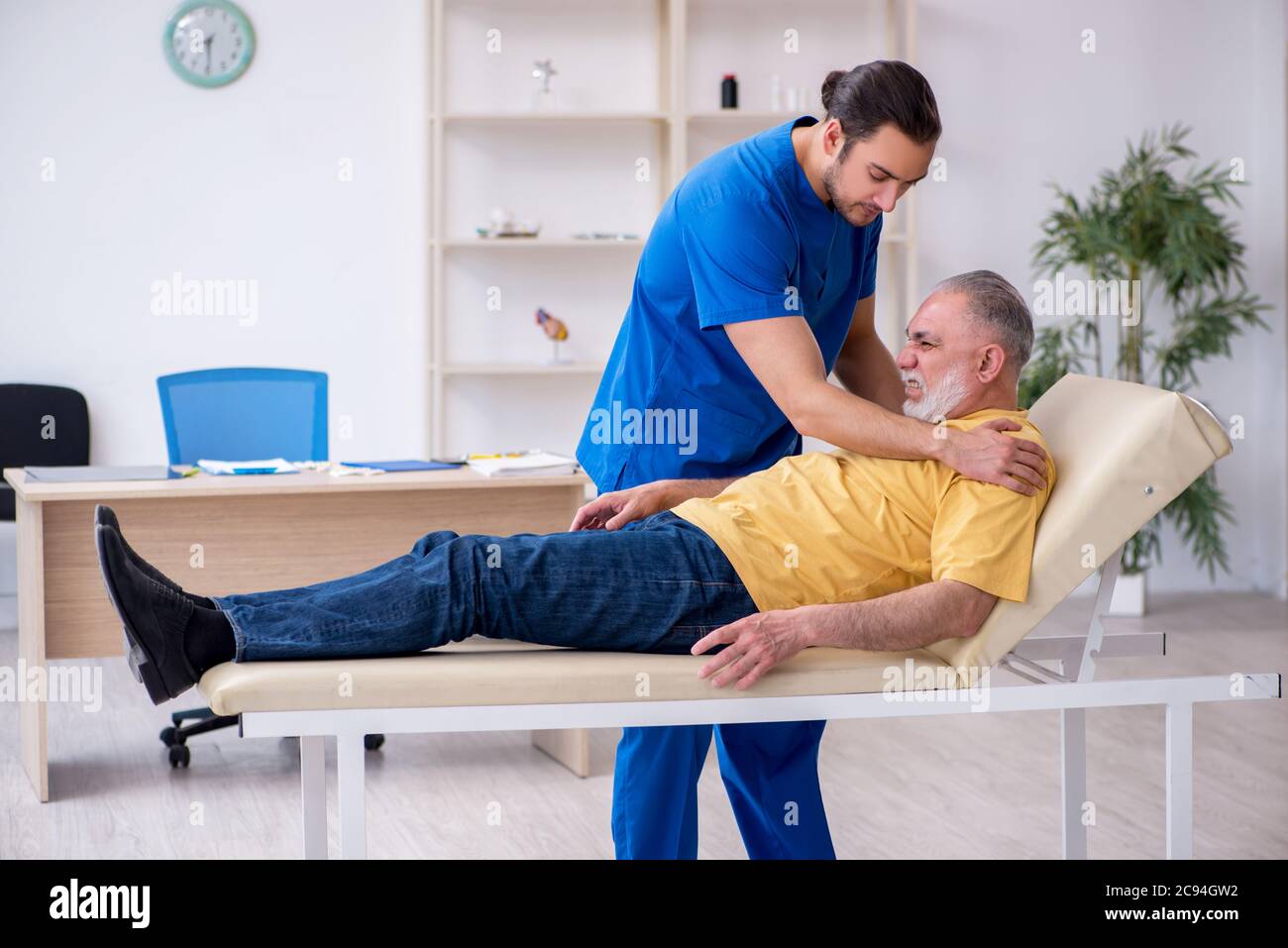 Old injured man visiting young doctor chiropractor Stock Photo - Alamy