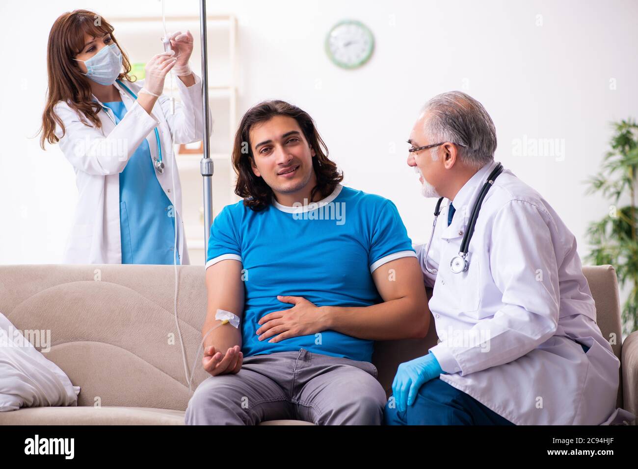 Two doctors visiting sick man at home Stock Photo - Alamy