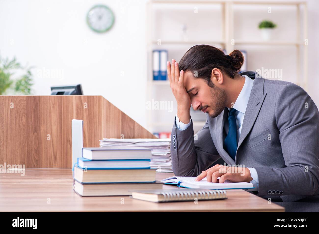Young businessman reading books at workplace Stock Photo - Alamy