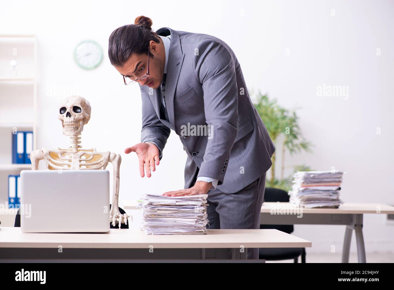 Young employee and skeleton in the office Stock Photo - Alamy