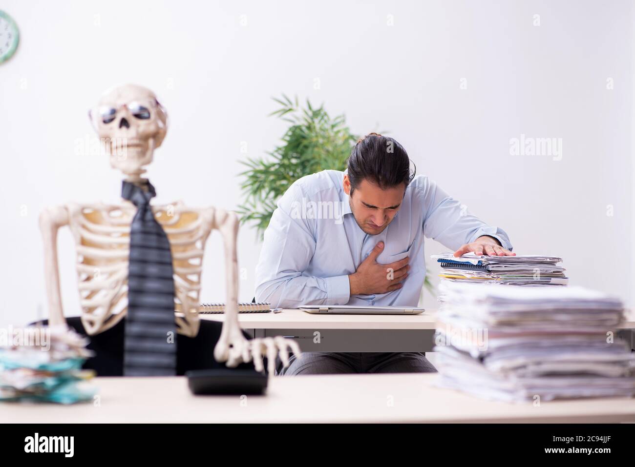 Young employee and skeleton in the office Stock Photo - Alamy