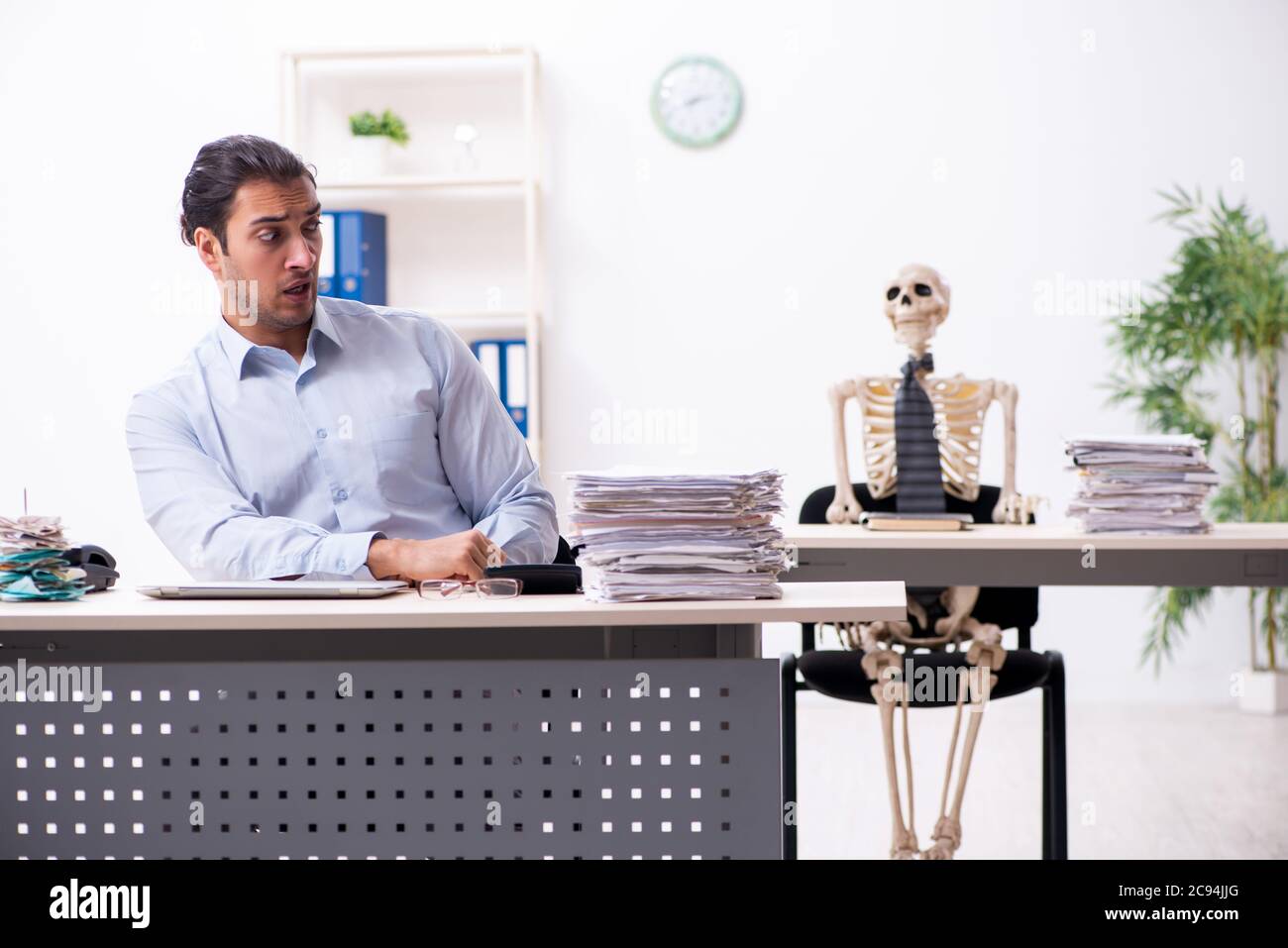 Young employee and skeleton in the office Stock Photo - Alamy