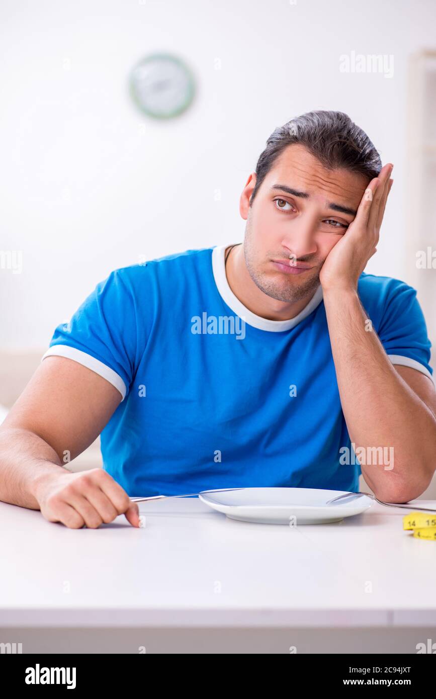 Young hungry man in the dieting concept Stock Photo - Alamy