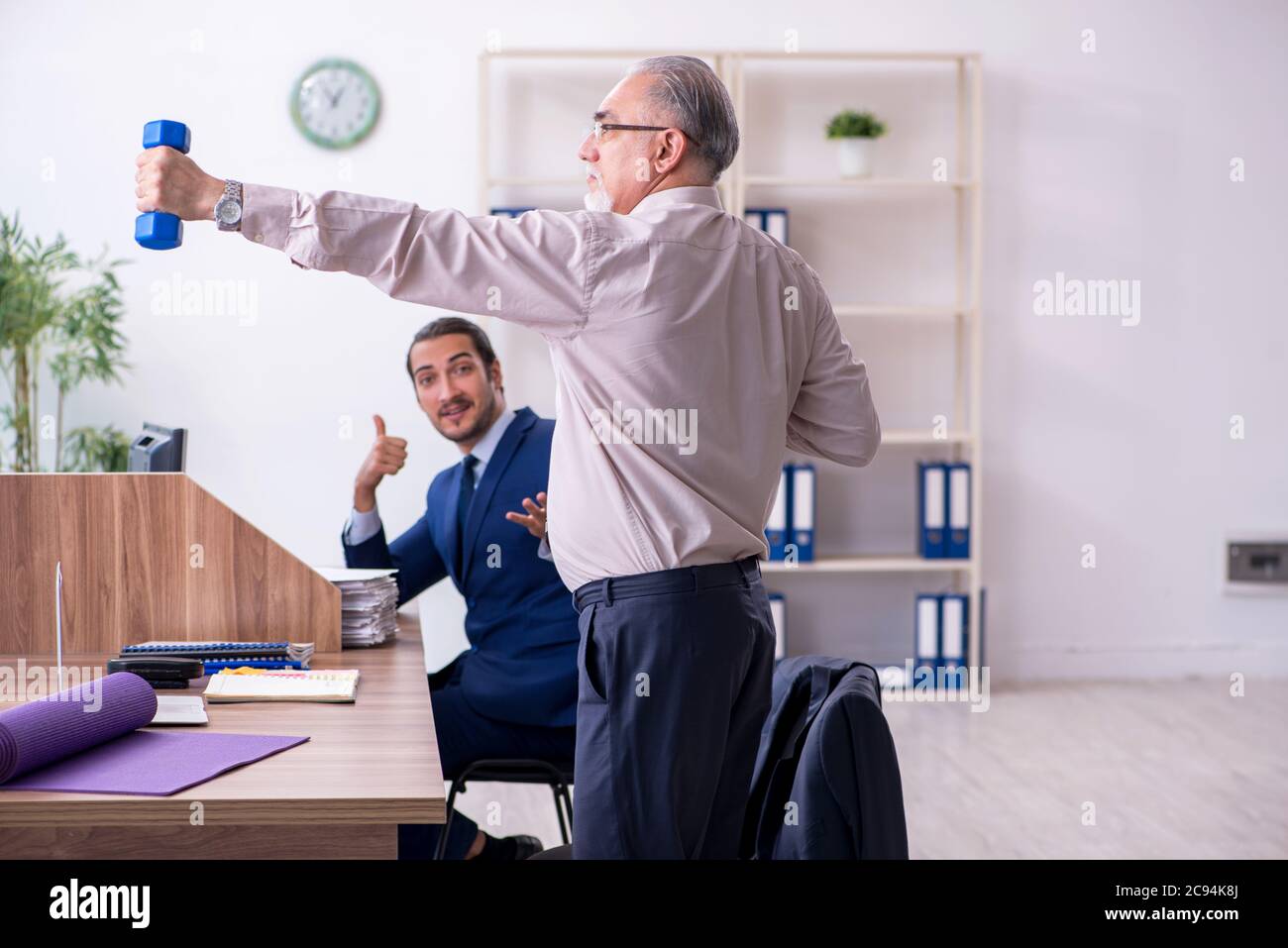 Two employees doing physical exercises at the workplace Stock Photo - Alamy