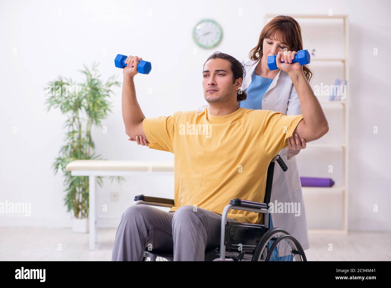 Young male patient in wheel-chair doing physical exercises in hospital ...