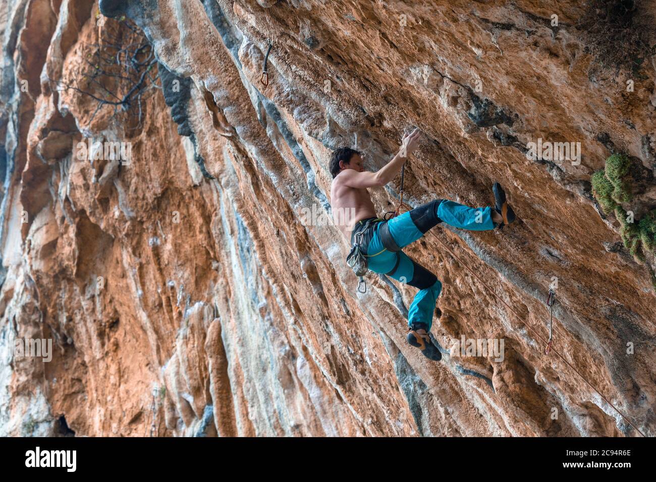 A man rock climber in bright blue pants climbing the challenging ...
