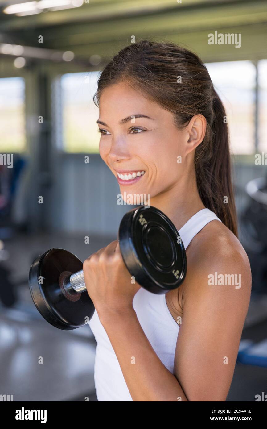 Asian woman strength training biceps with free weights at gym, lifting ...