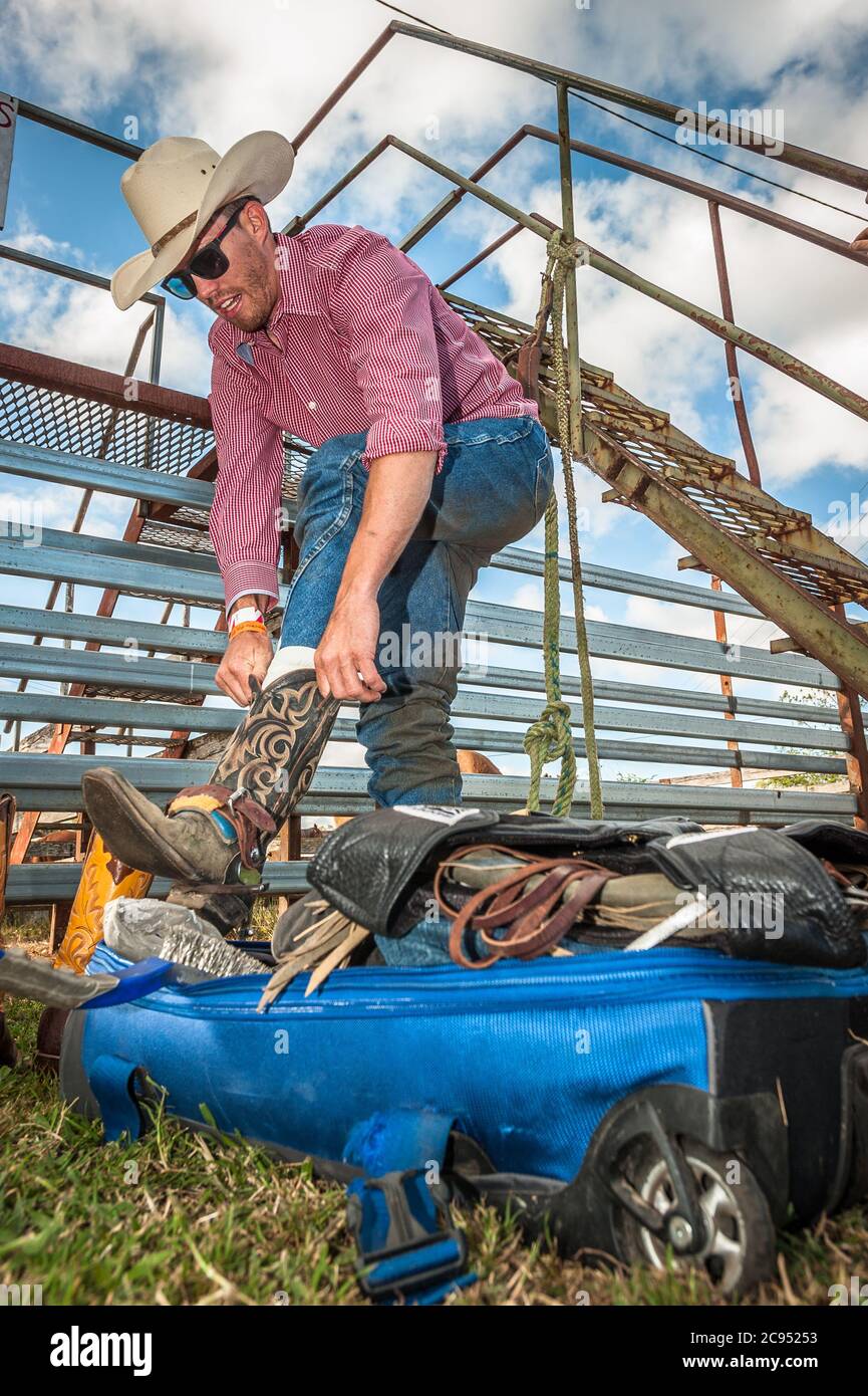 A low perspective view of a cowboy slipping on his riding boots in ...
