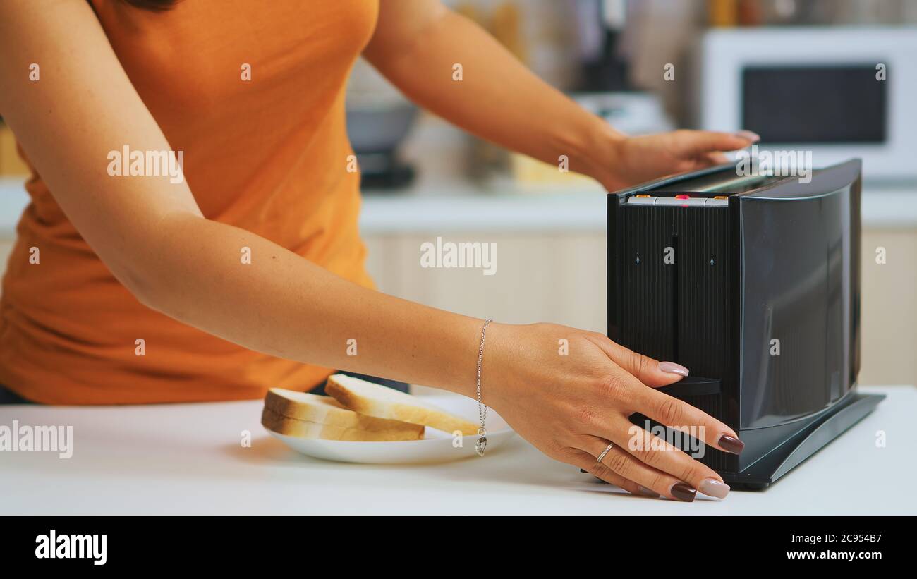Woman making roasted bread using toaster. Housewife using bread toaster ...