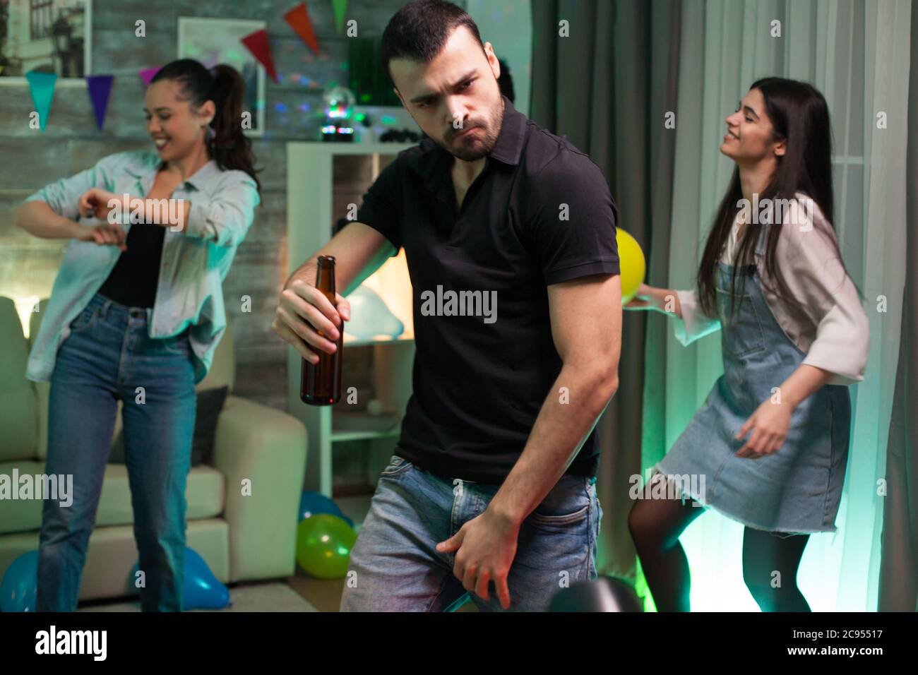 Attractive young man with a beer bottle in his hand dancing at a party ...