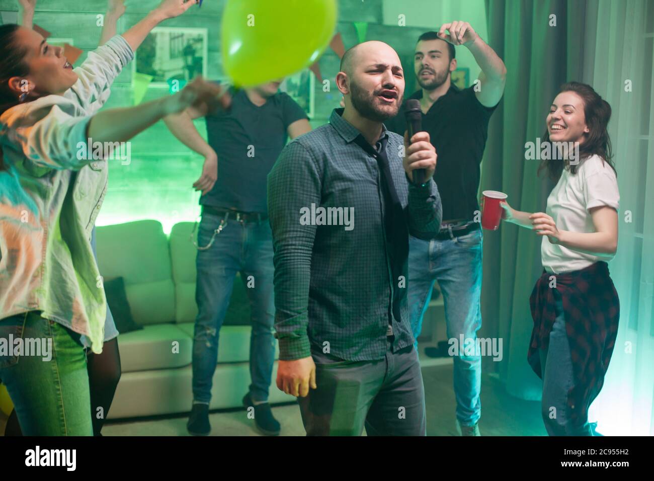 Cheerful bald man doing karaoke for his friends at the party Stock ...