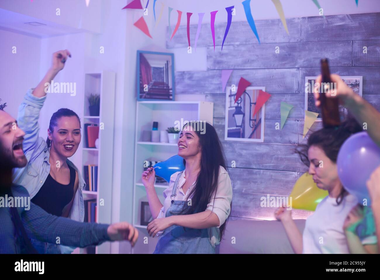 Excited beautiful young woman dancing with her friends at the party ...