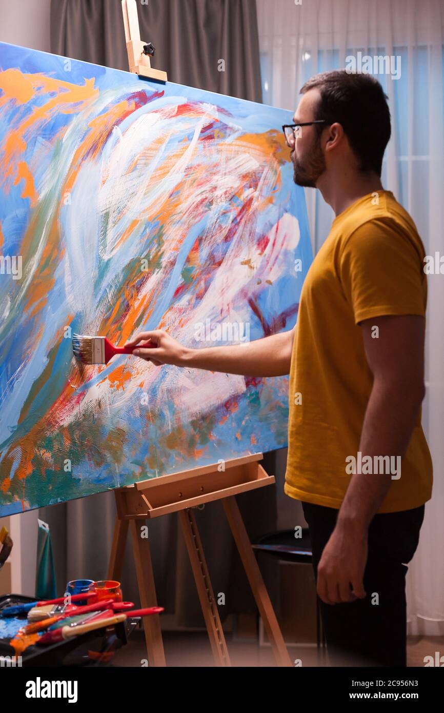 Artist with glasses painting a masterpiece in art workshop. Modern ...