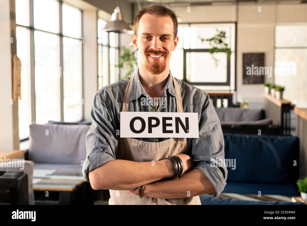 Portrait of cheerful confident young coffee shop owner with Open sign ...