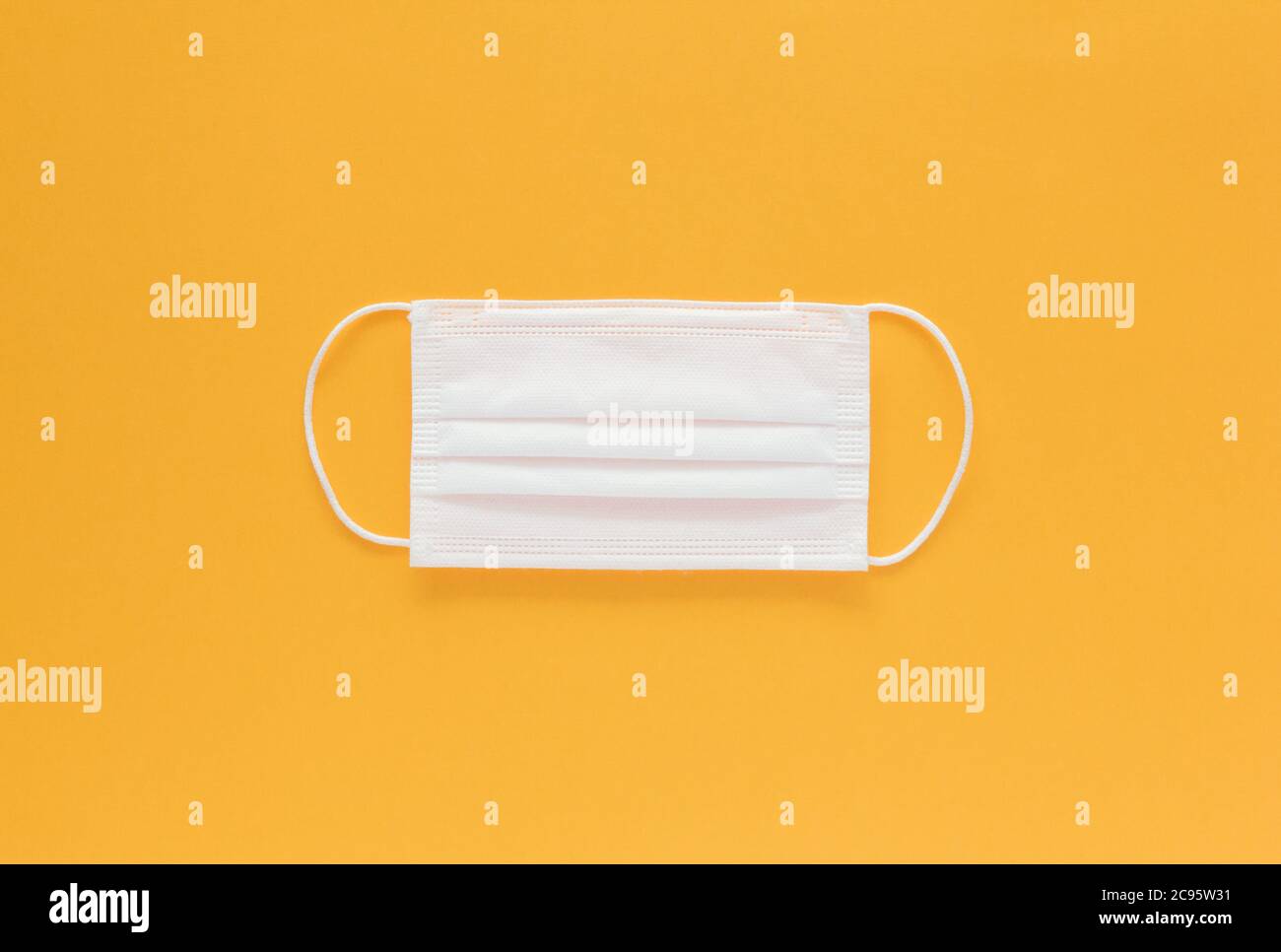 Stock photo of an isolated face mask in the middle on a yellow ...