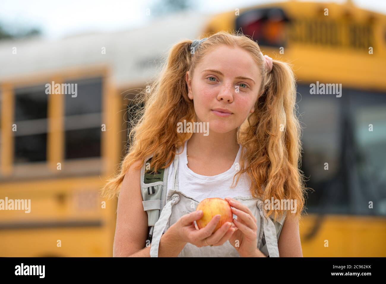 School girl at the front of the school bus with apple Stock Photo - Alamy