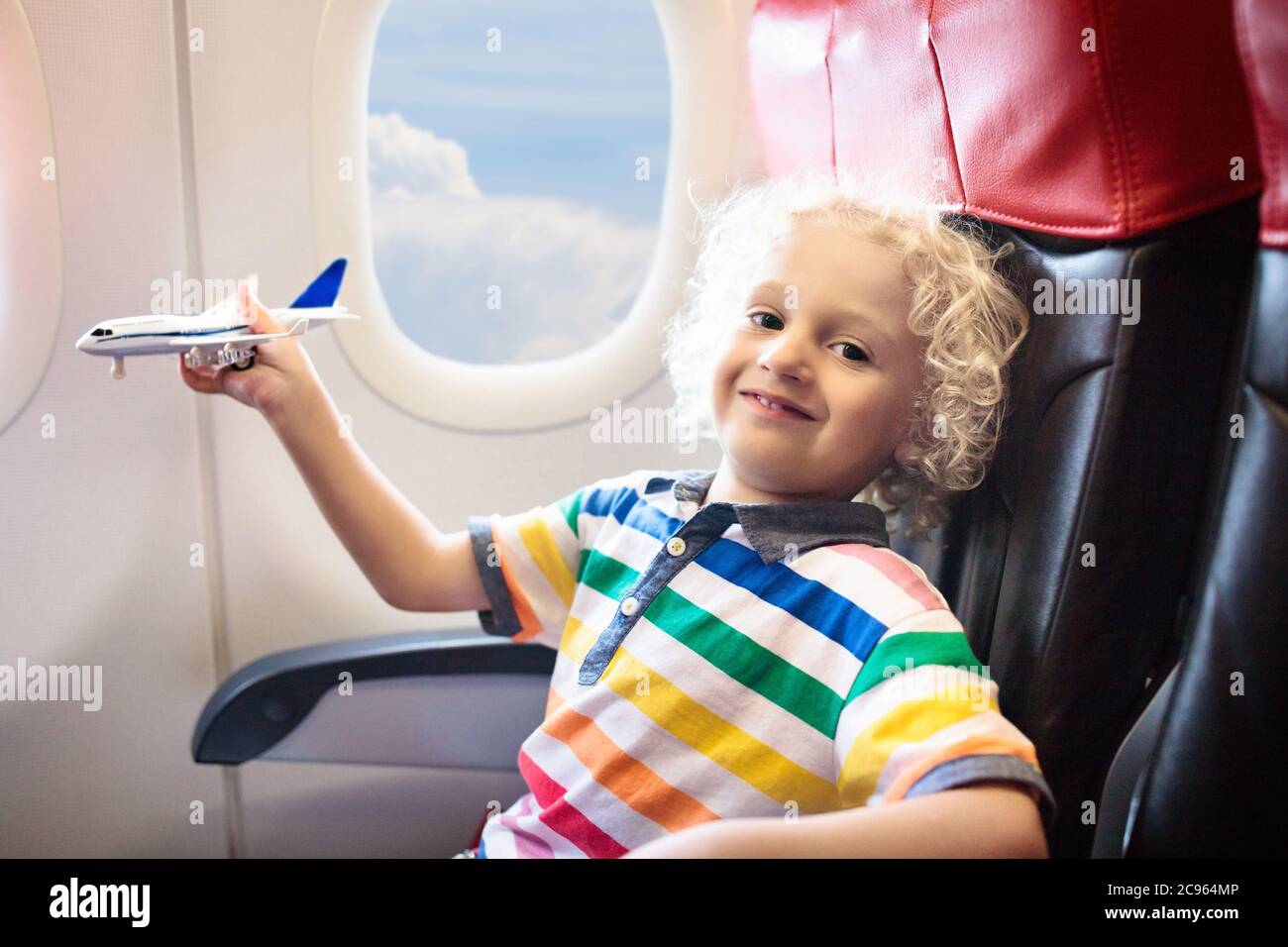 Child in airplane. Kid in air plane sitting in window seat. Flight ...