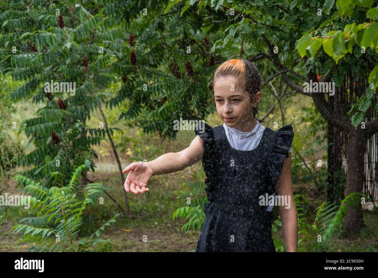 Wet schoolgirl standing in the rain. teenager in school uniform in ...