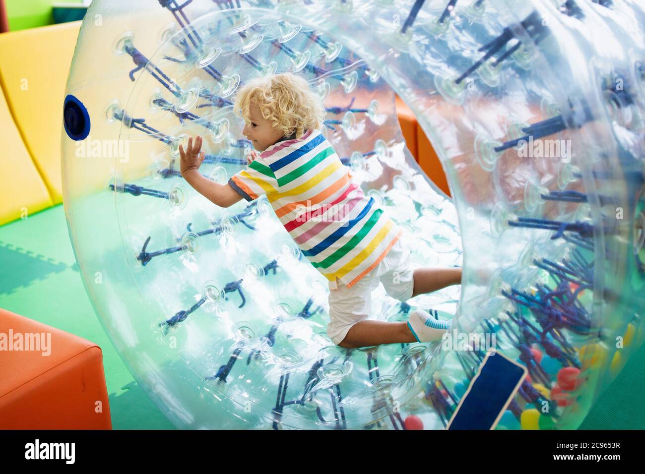 Child in roller wheel jumping on colorful playground trampoline. Kids ...