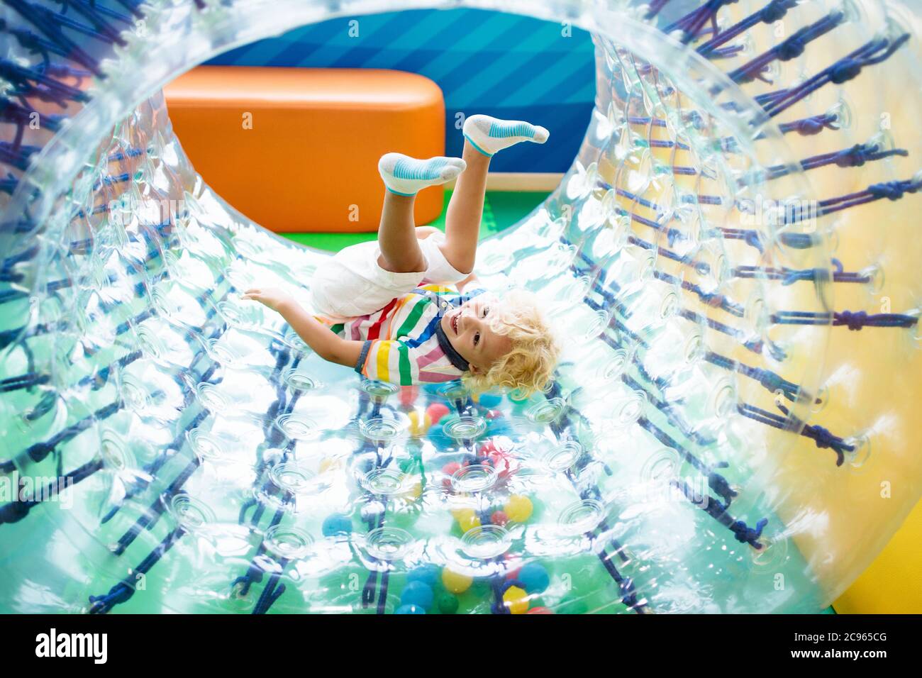 Child in roller wheel jumping on colorful playground trampoline. Kids ...