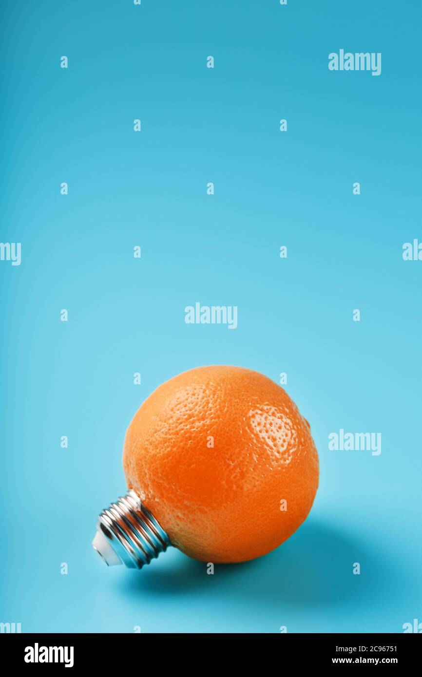 Orange light bulb on a blue background. The concept of fruit ideas ...