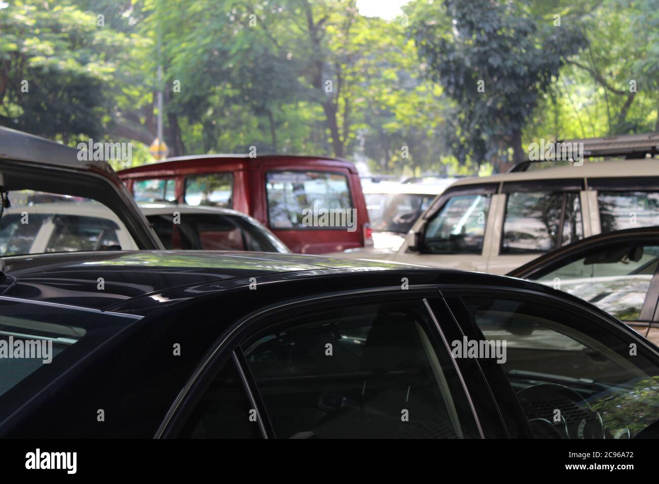 Random cars are parked on a parking area under daylight. Cropped view ...