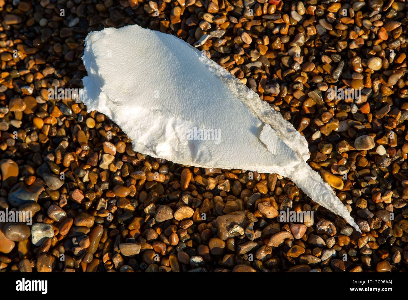 Lump of white polystyrene pollution washed up on shingle beach close up ...