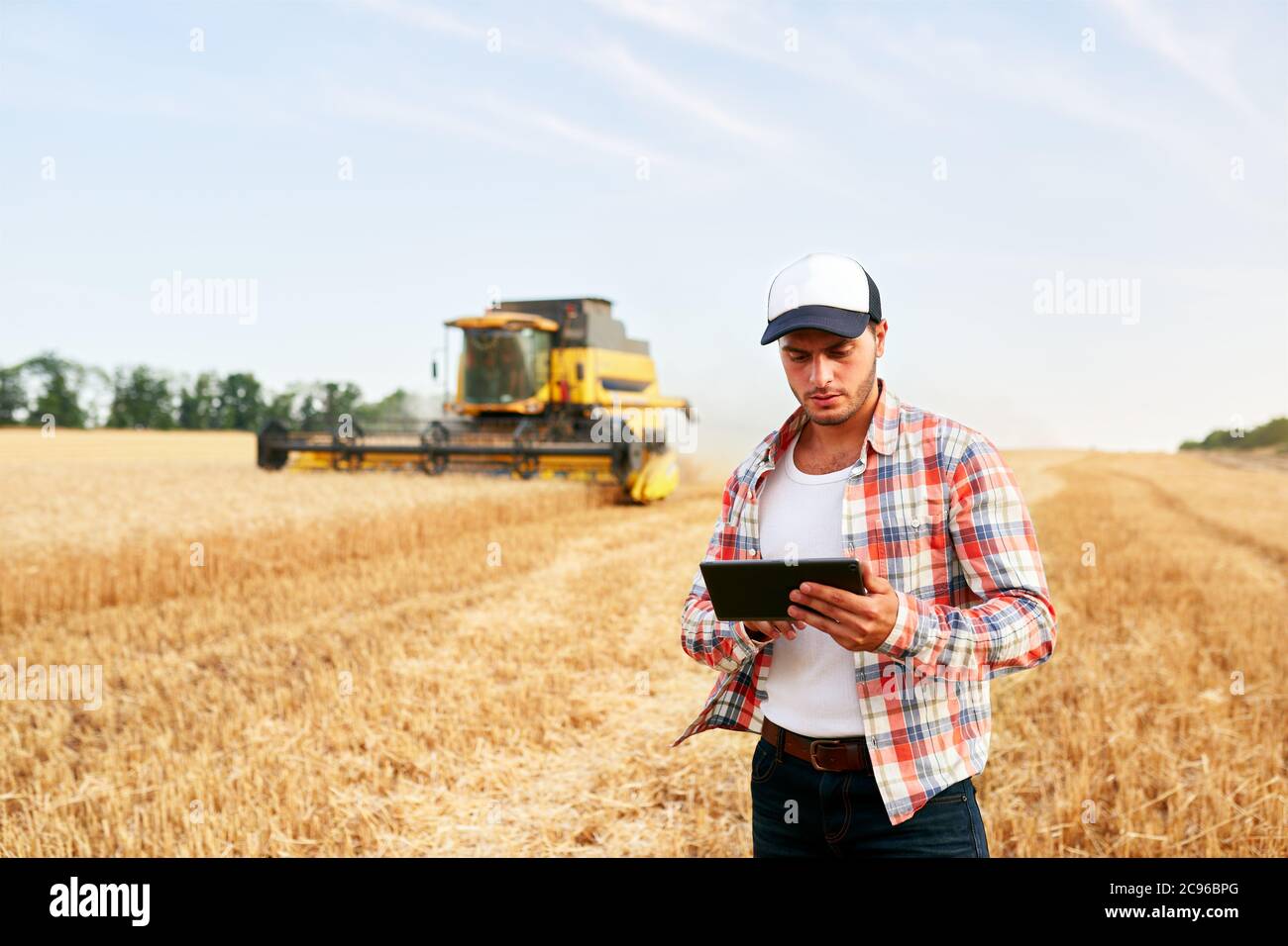 Precision farming. Farmer holding tablet for combine harvester guidance ... Precision farming. Farmer holding tablet for combine harvester guidance ...