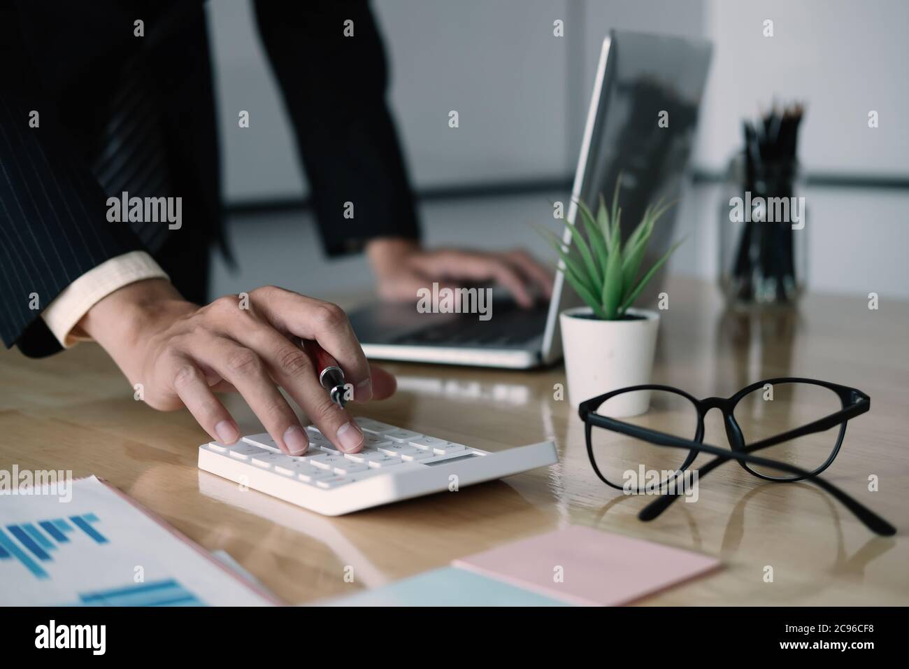 Close up of businessman or accountant hand holding pen working on ...