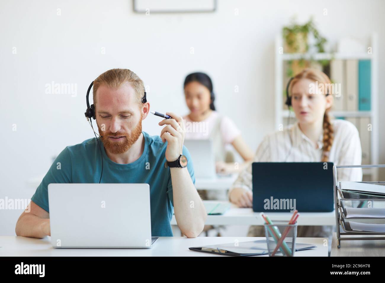 Group of operators sitting at the table with computers they working in ...