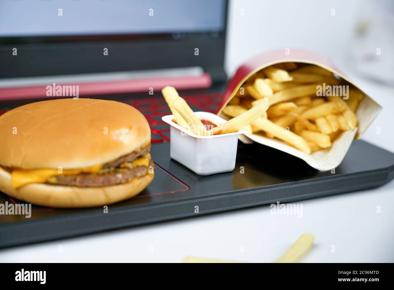 fast food lies near a laptop computer, fries and burger Stock Photo - Alamy