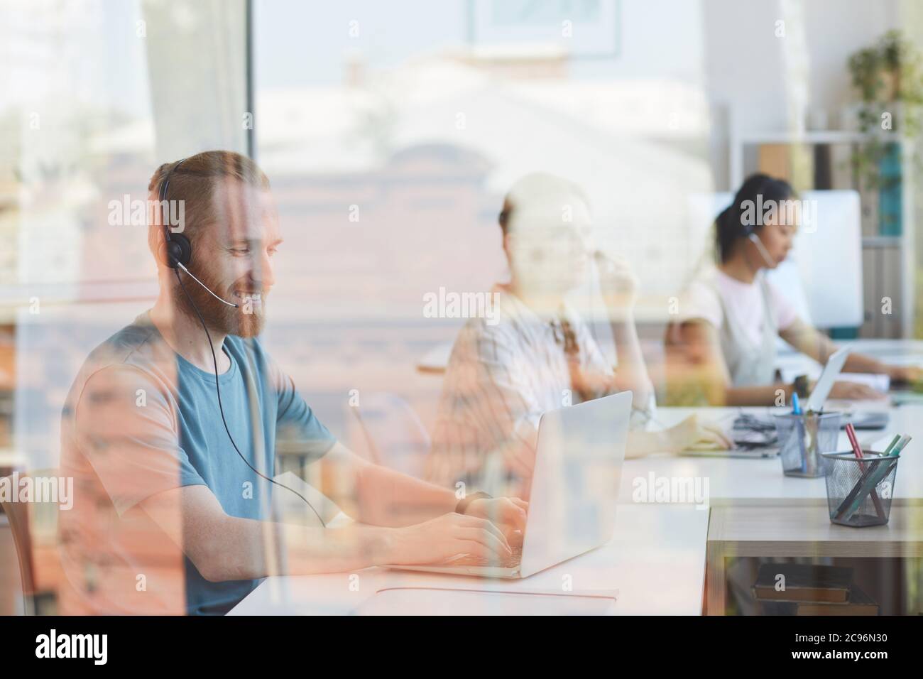 Business people sitting at their workplaces and working on computers at ...