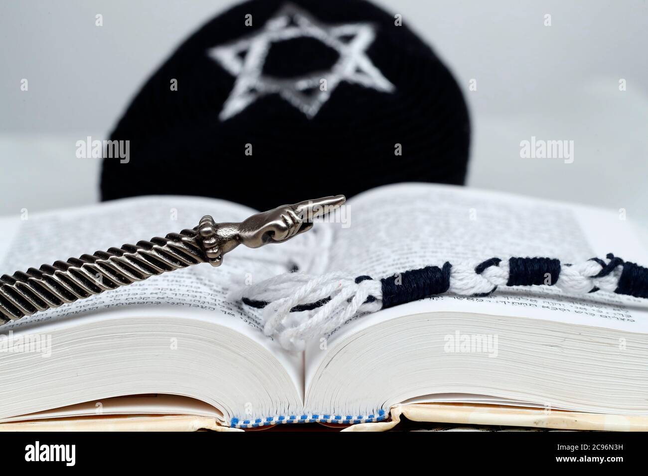 Sylver yad, black and white tzitzit, kippah and Torah. Jewish symbols ...