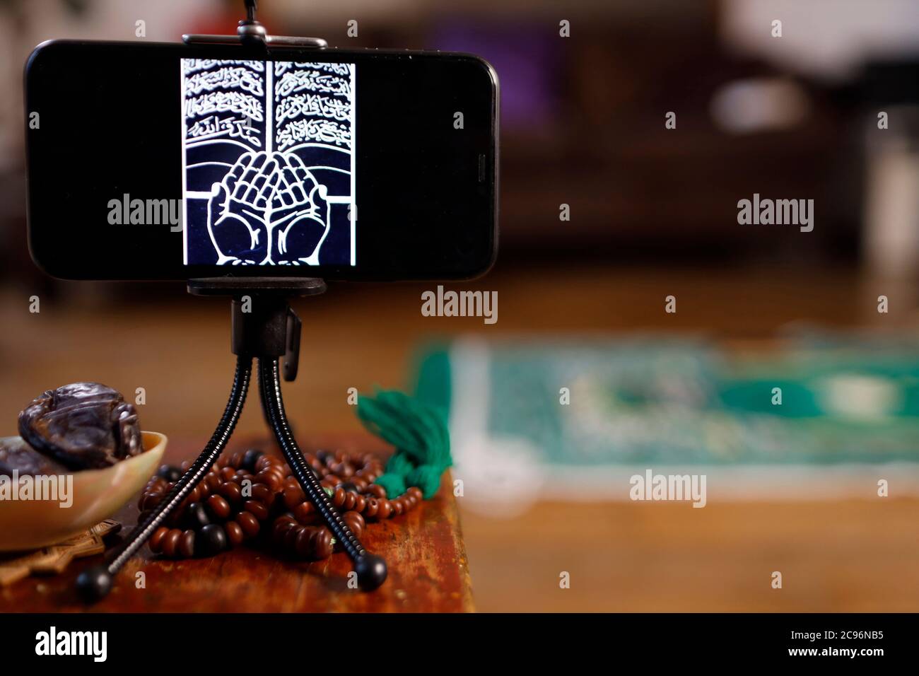 Smartphone wiht hands praying image and muslim prayer mat at home ...