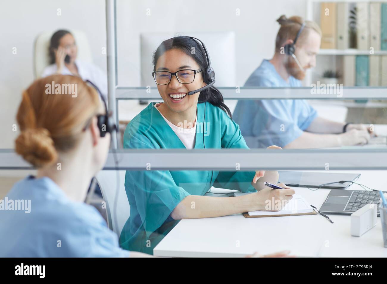 Two operators in headphones talking and laughing at the table during ...