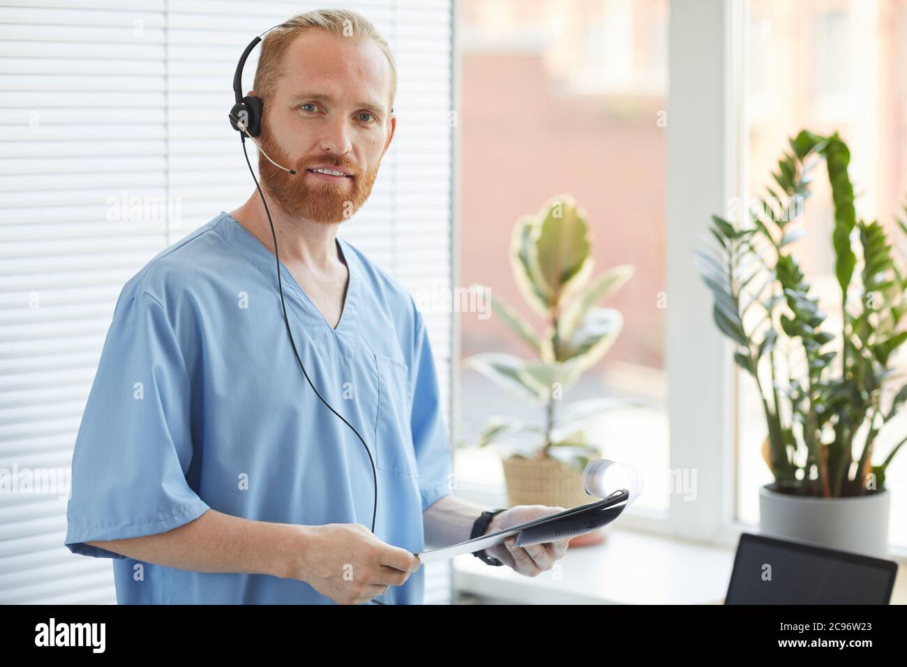Portrait of male medical operator in uniform and headset smiling at ...