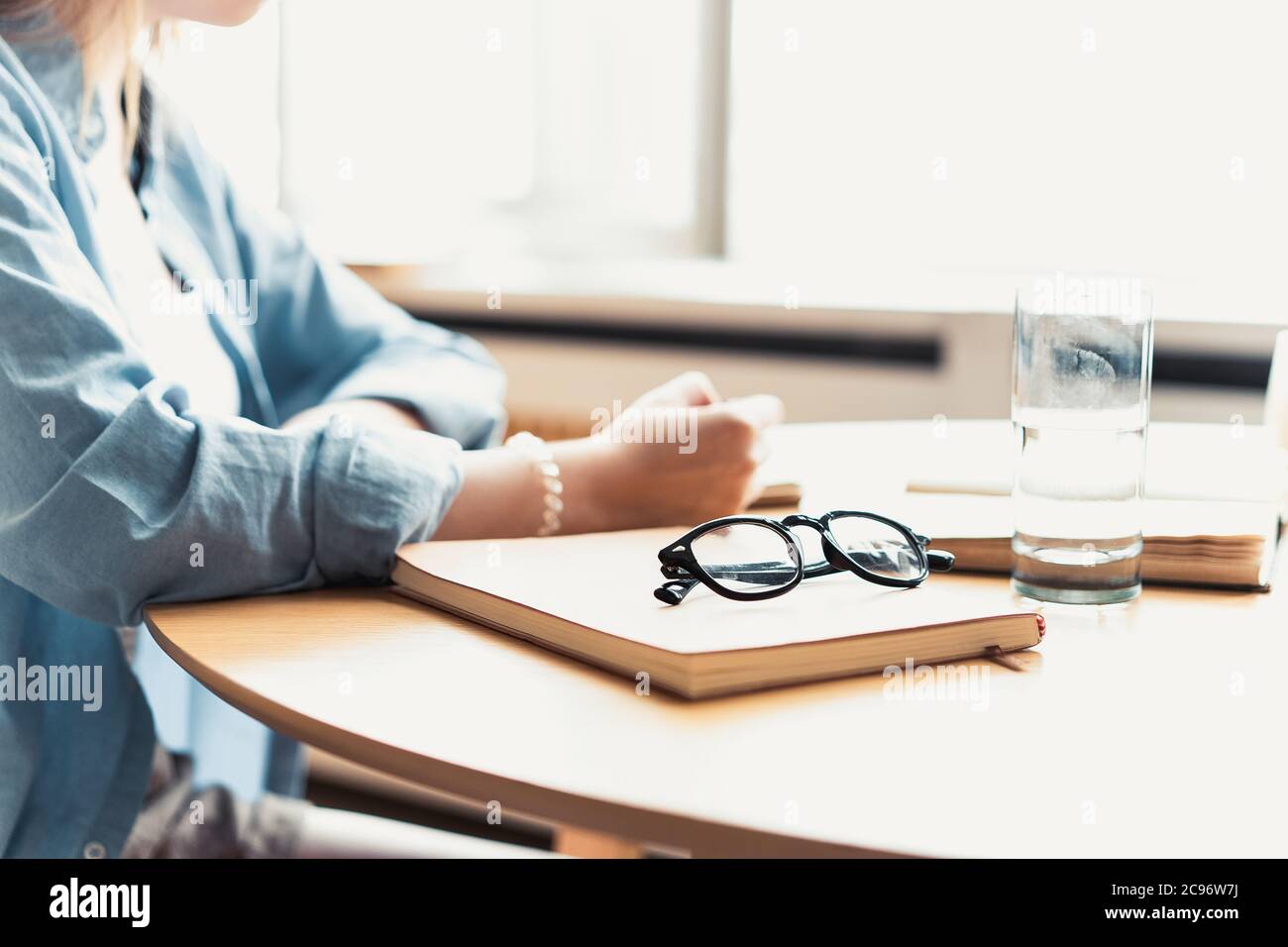 Focused young woman writing letter on table at home office ...