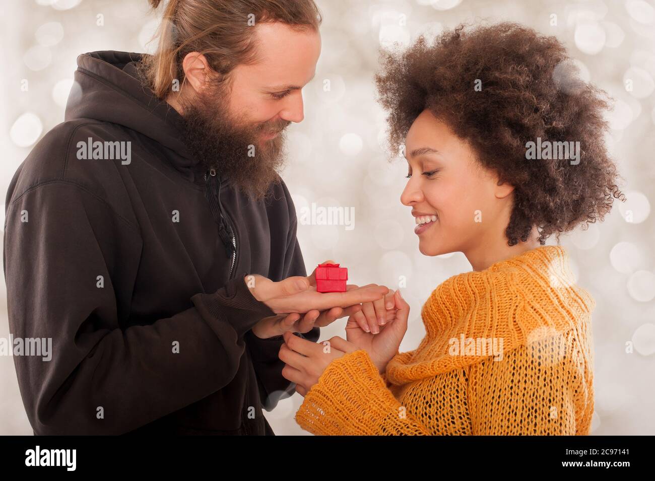 Happy man giving engagement ring in little red gift box to woman over ...