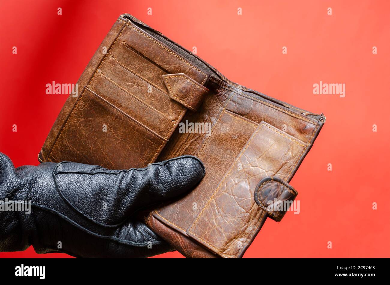 Hand in black leather glove holds out empty brown wallet. Male hand ...