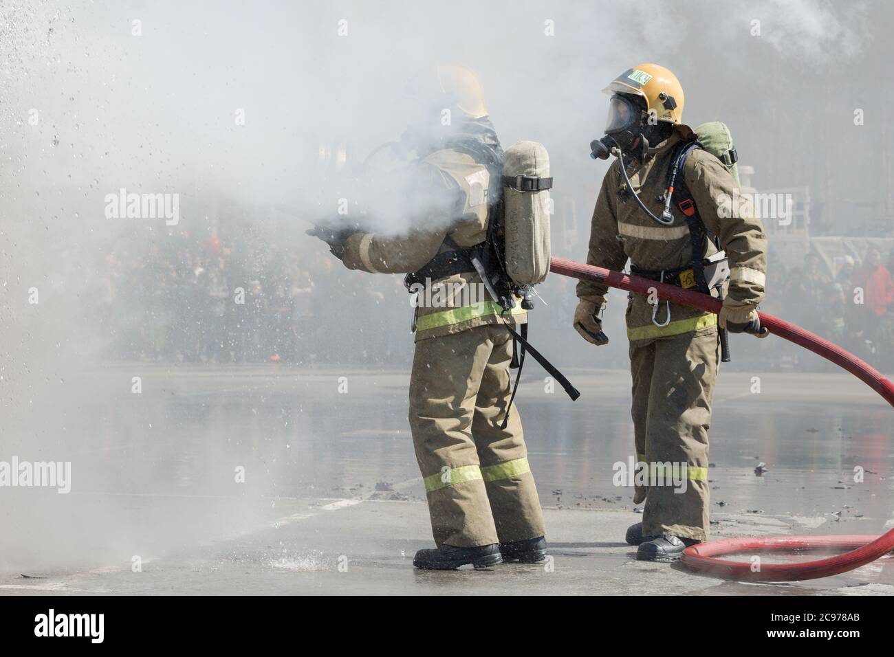 Two firefighters extinguishes fire from fire hose, using firefighting ...