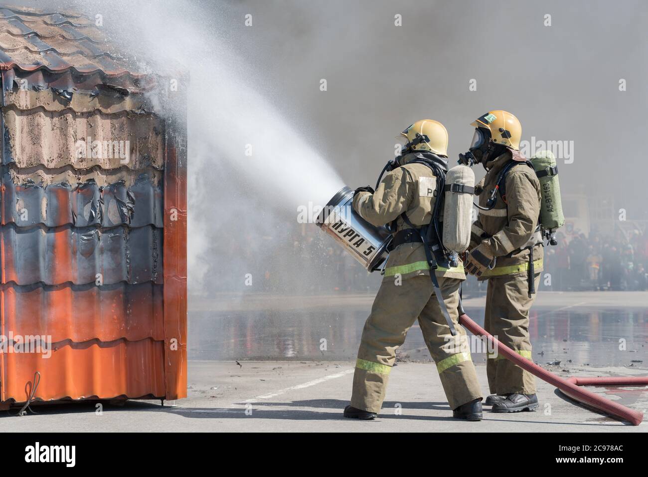 Two firefighters extinguishes fire from fire hose, using firefighting ...