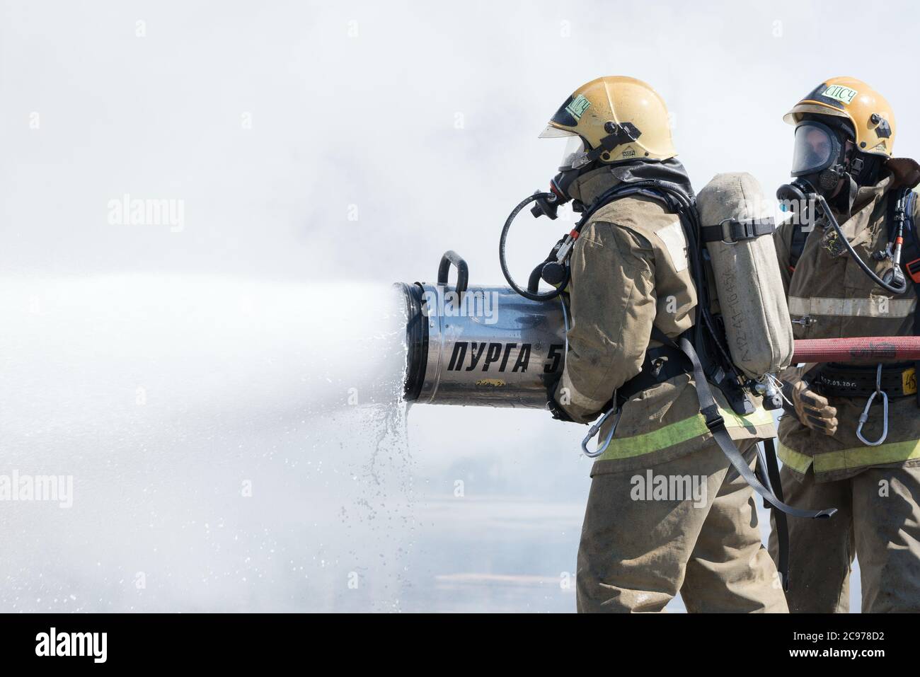 Two firefighters extinguish fire from fire hose, using firefighting ...
