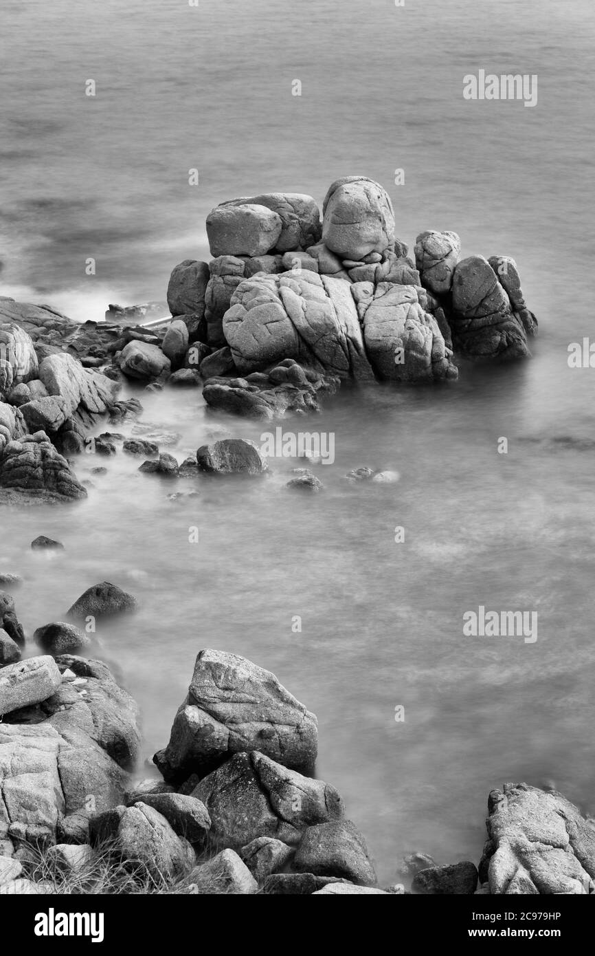 Vertical greyscale of the rocks in the middle of the ocean captured on ...