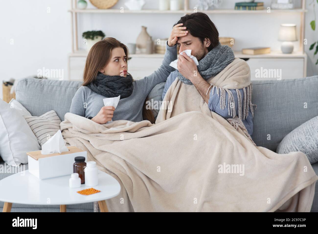 Sick couple covred in blanket sitting on couch, having fever Stock ...