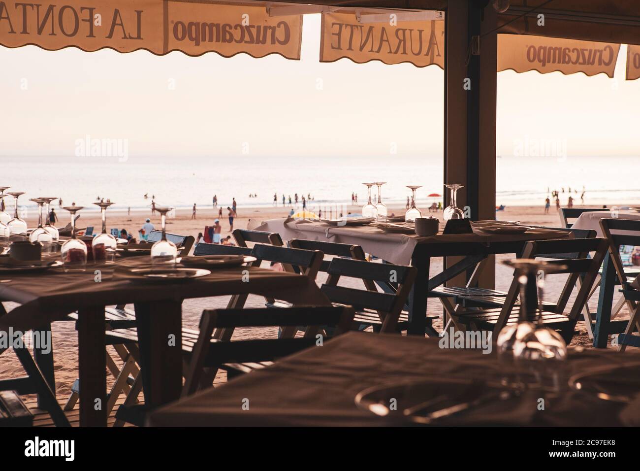 Tables wait fro customers at a beach side restaurant on the south coast ...