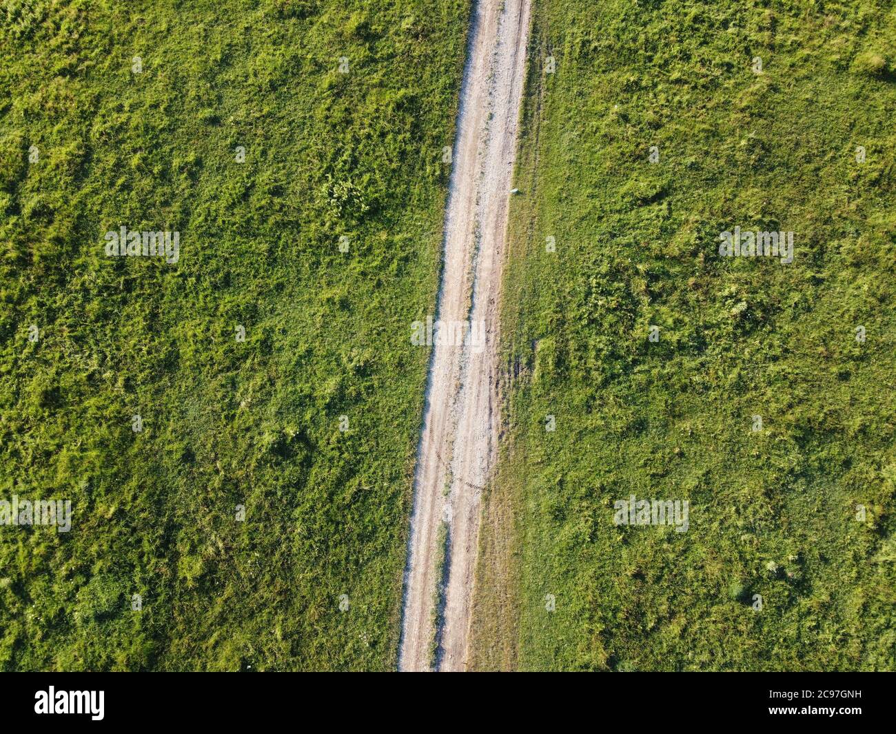 Aerial top view of a dirt road leading through a green field Stock ...